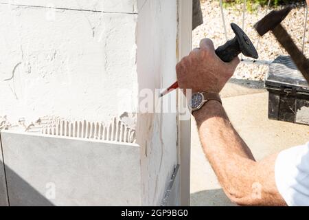 the mason prepares the wall with a chisel before laying a ceramic tile ...
