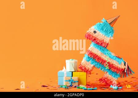 Mexican pinata with party hat, gifts and balloons on color background ...