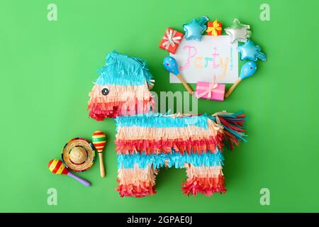 Mexican pinata with sombrero hat, maracas and balloons on color ...