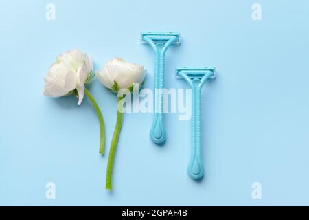 Safety shaving razors and ranunculus flowers on white wooden background ...