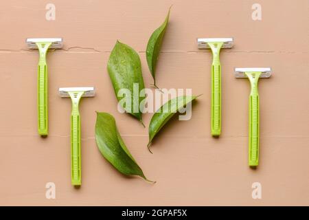 Safety razors and green leaves on color wooden background Stock Photo ...
