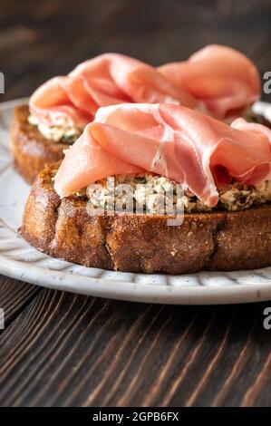 Delicious bruschettas with cream cheese, prosciutto, tomatoes and ...