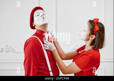Two mime artists in red costumes, kissing scene. Pantomime theater ...