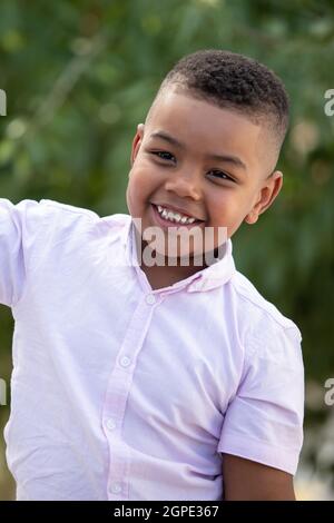 Adorable latin child in the garden with a beautiful green of background ...