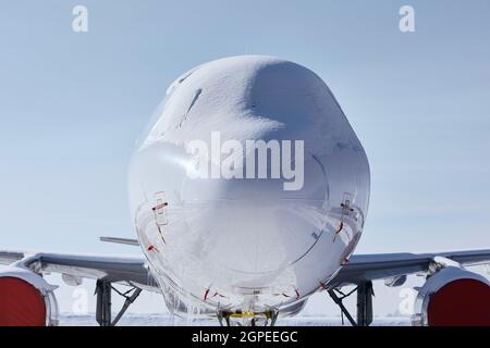 Snow covered commercial plane at the airport. Close-up of the plane ...