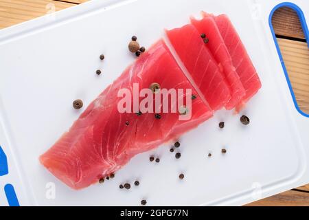 One piece of slightly salted tuna meat on a slate stone, close-up, top ...