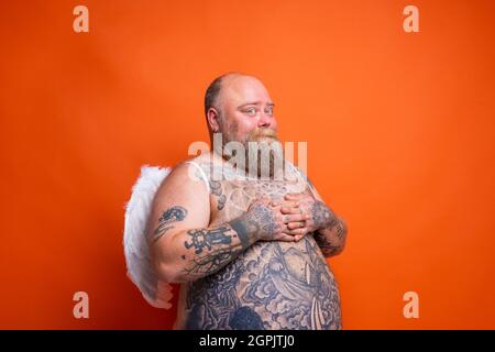 Fat man with beard ,tattoos and wings acts like an angel Stock Photo ...