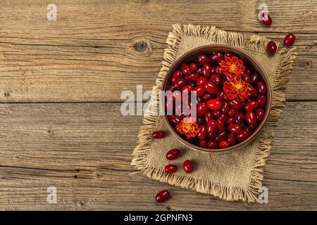 Ripe dogwood berry with bright marigold flowers. Fresh red Cornus in a ...
