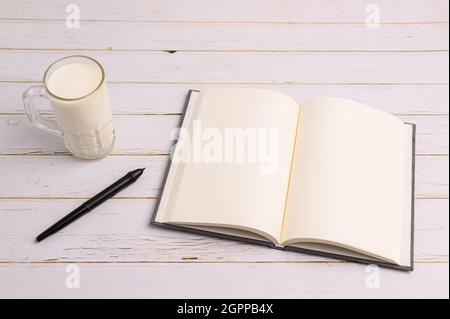 The notebook and a glass of milk are on the desk Stock Photo - Alamy