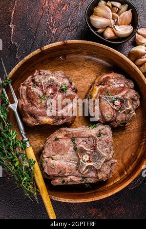 Fried lamb neck meat steaks in a wooden plate with herbs. Dark ...