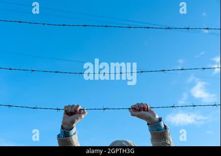 Lady's hand clinging to wire mesh, Behind the barrier Stock Photo - Alamy