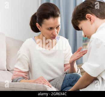 Strict mother scolding unhappy teen daughter at home, child feeling afraid covering ears with ...