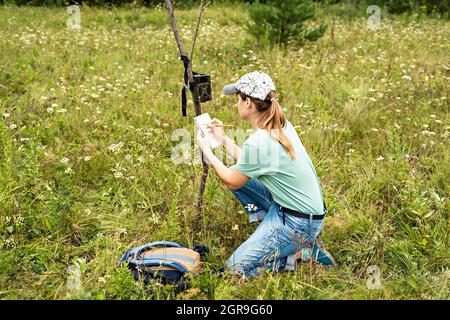 Young woman scientist biologist zoologist sets camera trap for ...