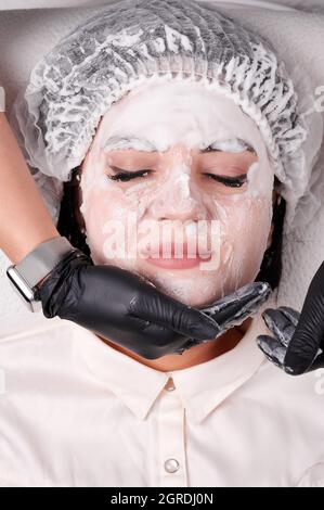 Beautician doctor applying facial cleansing foam on woman's face ...