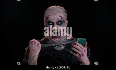 Sinister man Halloween zombie alone using mobile phone typing new post ...