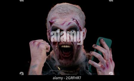 Sinister man Halloween zombie alone using mobile phone typing new post ...
