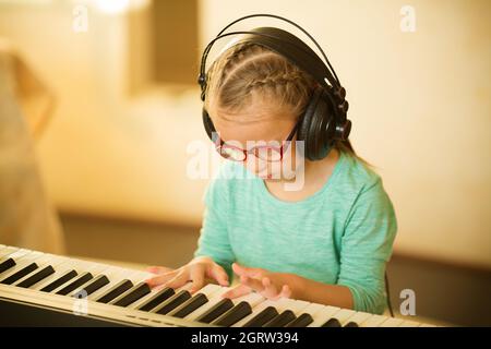 A girl with Down syndrome learns to play the piano and listens to music Stock Photo - Alamy