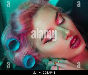 Portrait of woman with hair curlers and magazine smoking a cigarette ...