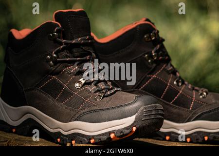 Closeup shot of a pair of dark grey hiking boots on a wooden texture ...