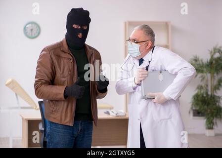 Burglar in balaclava bribing old doctor for getting vaccine Stock Photo ...