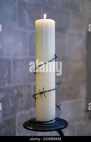 Burning candle with barbed wire on dark background. International ...