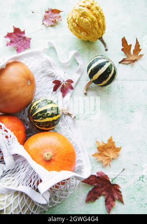 Ripe pumpkins in mesh bag on a wooden background. Eco-friendly farm ...