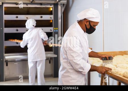 Baker dividing raw dough into equal parts in bakery Stock Photo - Alamy