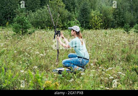 Young woman scientist biologist zoologist sets camera trap for ...