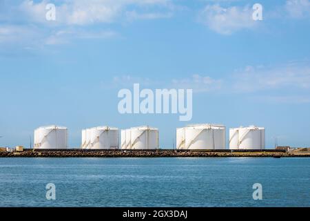 Industrial fuel storage tanks at marine terminal on coastline with ...