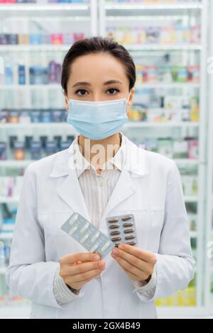 apothecary in medical mask holding blister pack with medication, banner ...