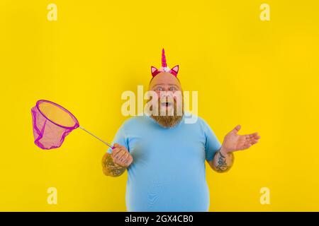 fat man with headband play with sea net and paddle Stock Photo - Alamy