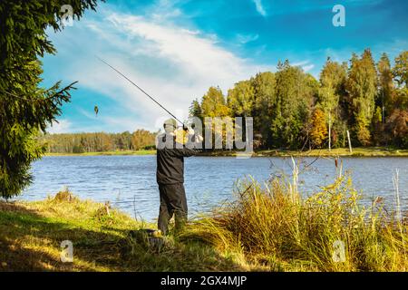 Fisher man fishing with spinning rod in a river at sunset Stock Photo ...