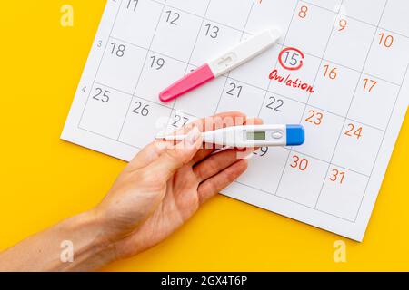 Female hand with thermometer over calendar basal temperature Stock ...