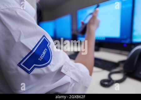 Female security operator holding portable radio in hand while working ...