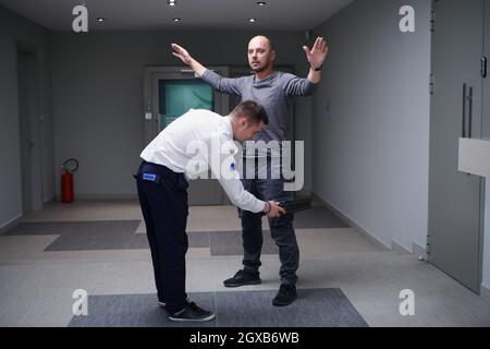Security guard making body searching procedure with a metal detector on ...