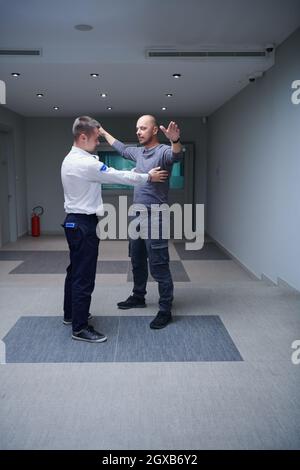 Security guard making body searching procedure with a metal detector on ...