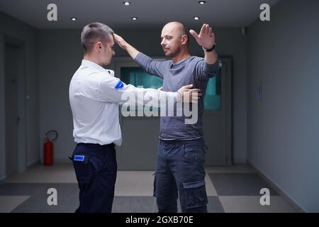 Security guard making body searching procedure with a metal detector on ...
