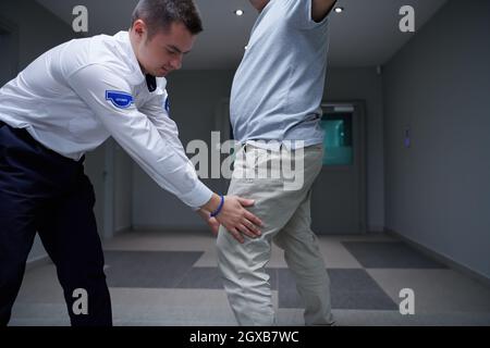 Security guard making body searching procedure with a metal detector on ...