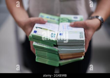 Bank employees holding a pile of paper banknotes while sorting and ...