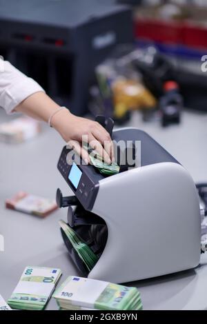 Bank employees using money counting machine while sorting and counting ...