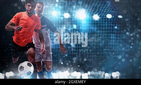 Two soccer players and a goalie chase the ball at the stadium Stock ...