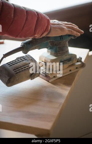 Man sanding wood plank using electric sand machine Stock Photo - Alamy