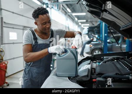 Male worker changes oil in engine, car service. Vehicle repairing ...