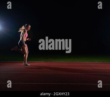 Athletic woman running onrace track Stock Photo - Alamy