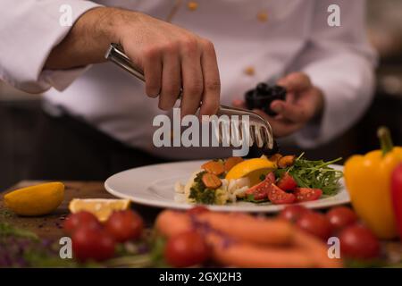 chef serving vegetable salad on plate in restaurant kitchen Stock Photo ...