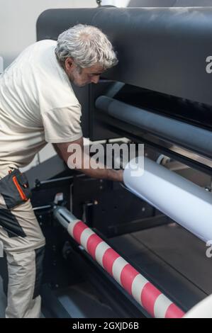 Technician worker operator changes the paper roll on large premium ...