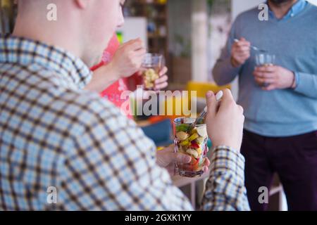 closeup of a young software developer eating a fruit salad from a clear ...