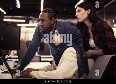 young multiethnics business team of software developers working together using laptop computer ...