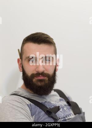 portrait of bearded hipster handyman with pen behind ear isolated on ...