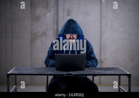 Young talented hacker smoking cigarette while working on laptop ...
